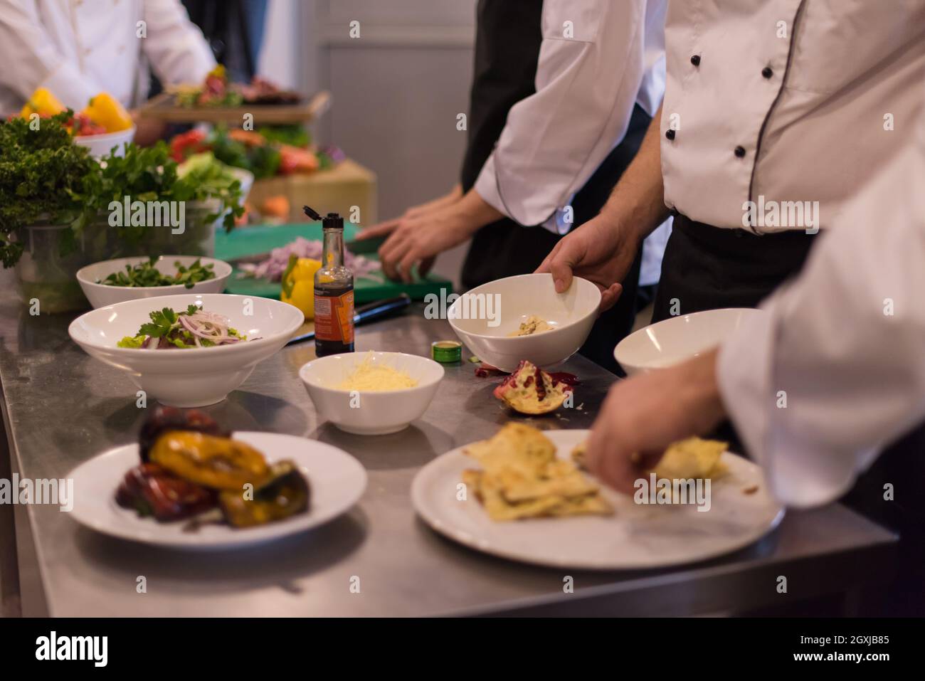 Professional team cooks and chefs preparing meal at busy hotel or ...