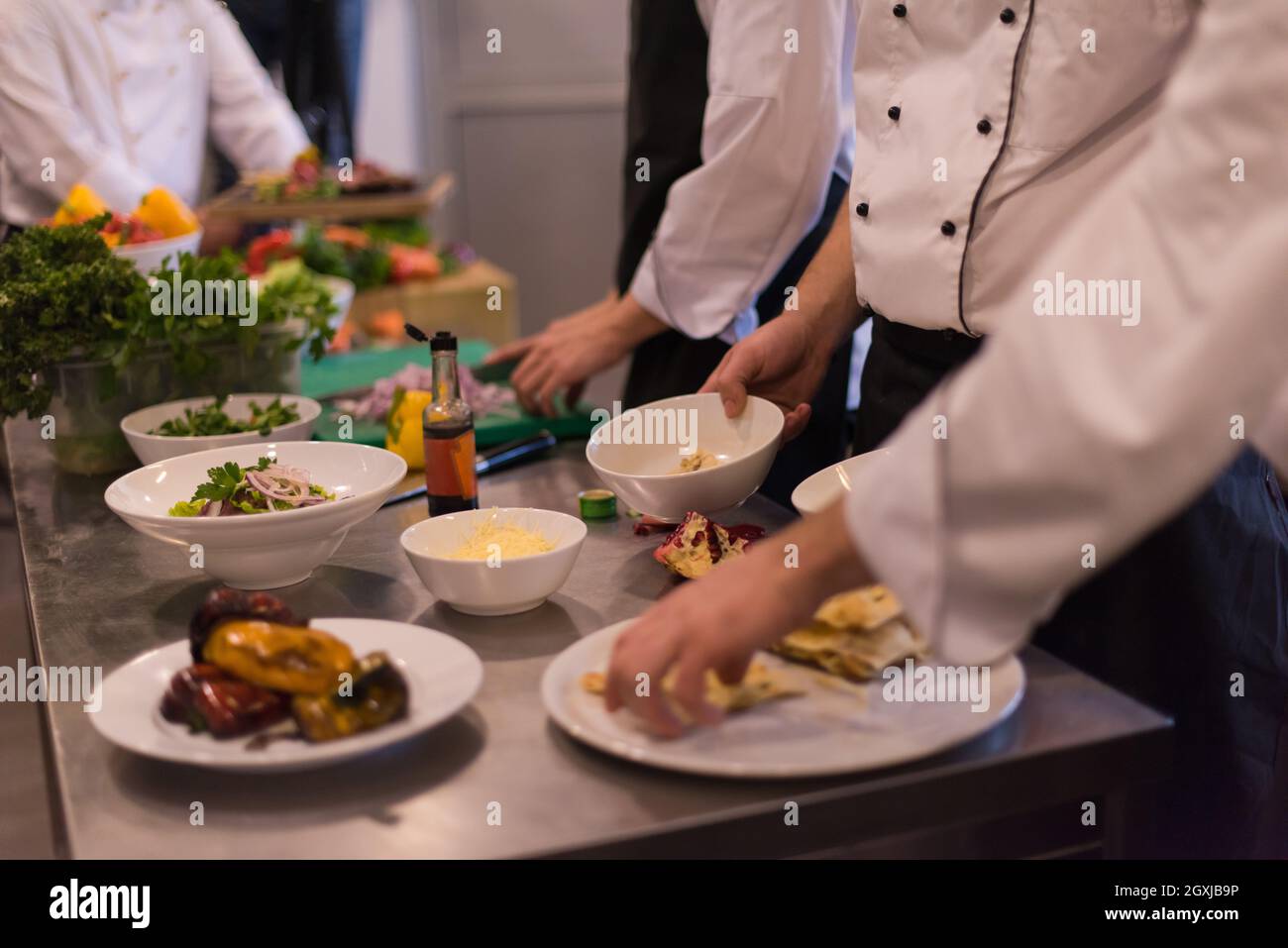 Professional team cooks and chefs preparing meal at busy hotel or ...