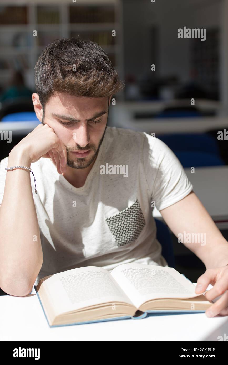 Student reading book in school library. Study lessons for exam. Hard ...