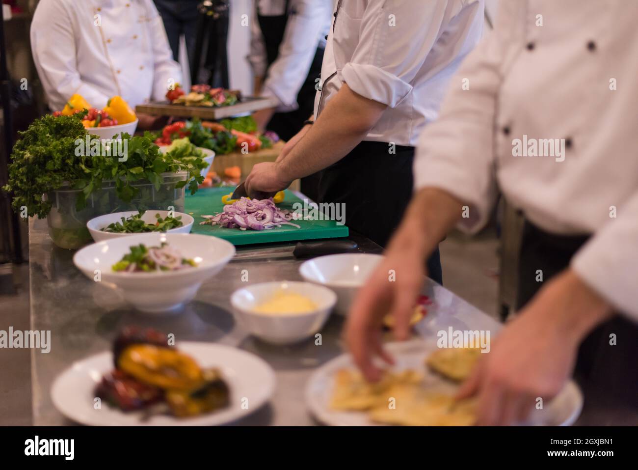 Professional team cooks and chefs preparing meal at busy hotel or ...