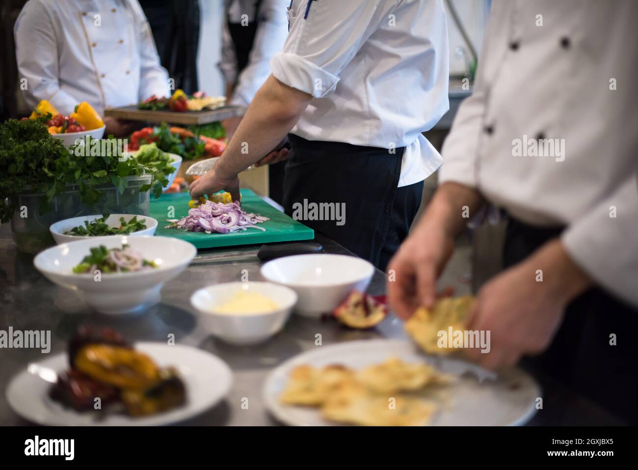 Professional team cooks and chefs preparing meal at busy hotel or ...