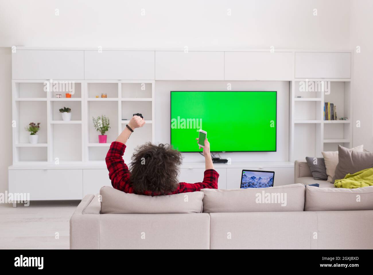young handsome man in bathrobe enjoying free time watching television ...