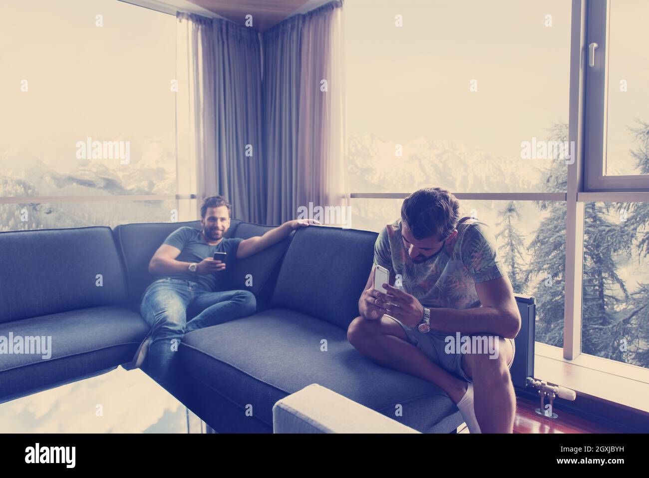 Handsome casual young men using a mobile phones near the window at home ...