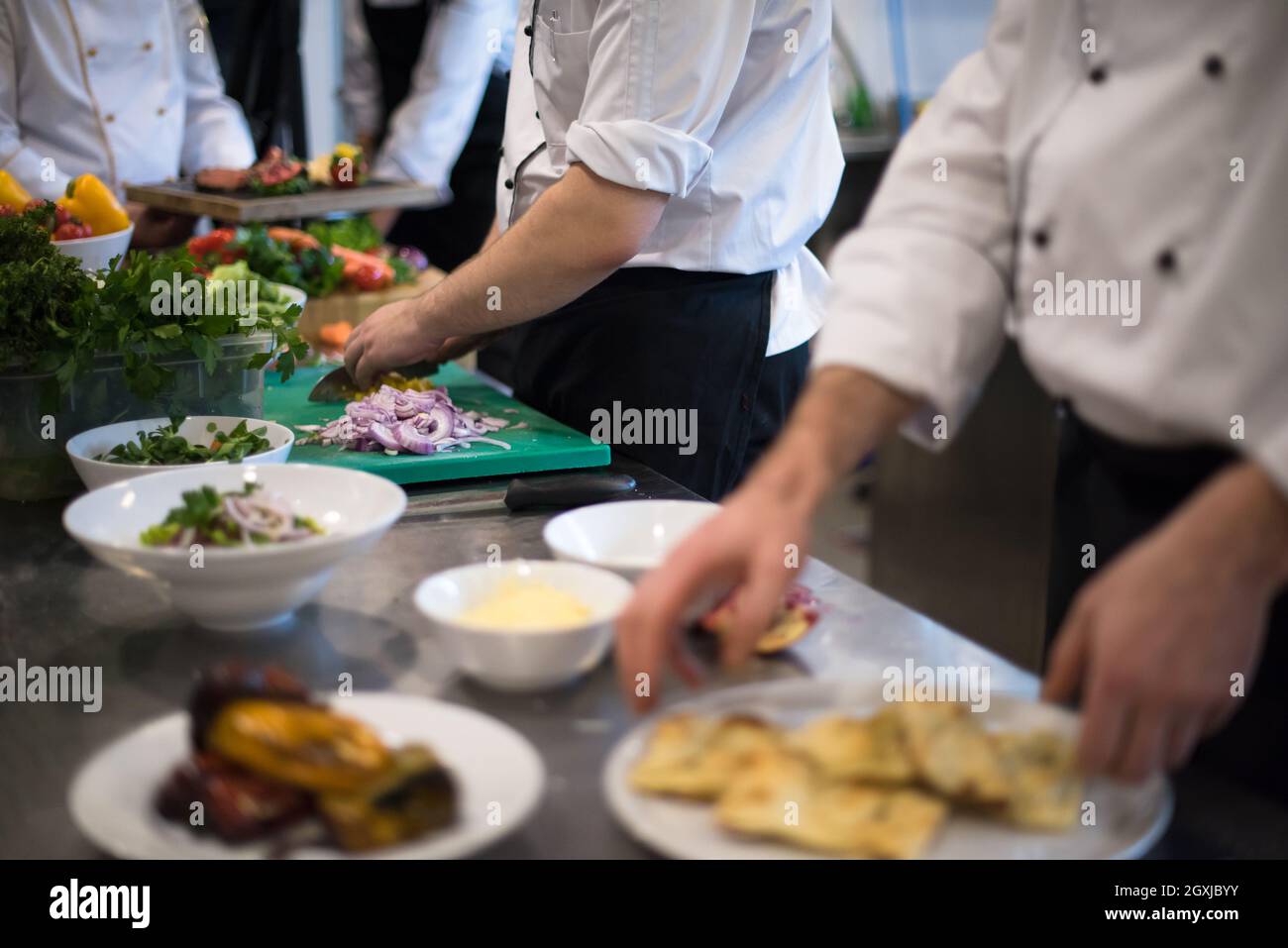 Professional team cooks and chefs preparing meal at busy hotel or ...