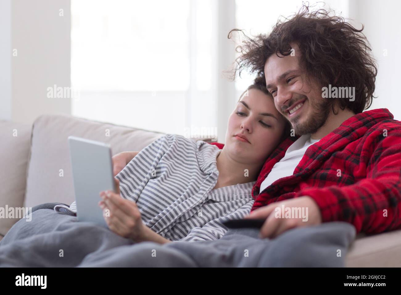 Young couple relaxing at home using tablet computers reading in the ...