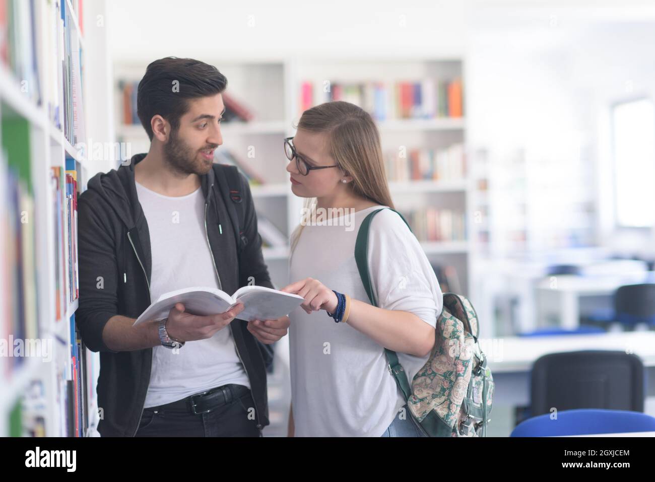 happy students couple in school library have discussion about book ...