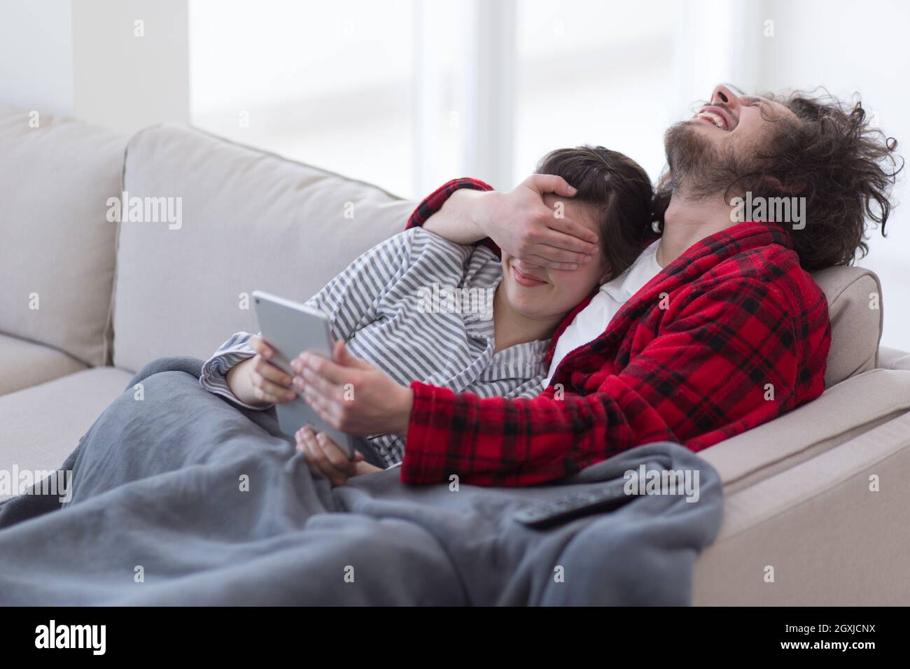 Young couple relaxing at home using tablet computers reading in the ...