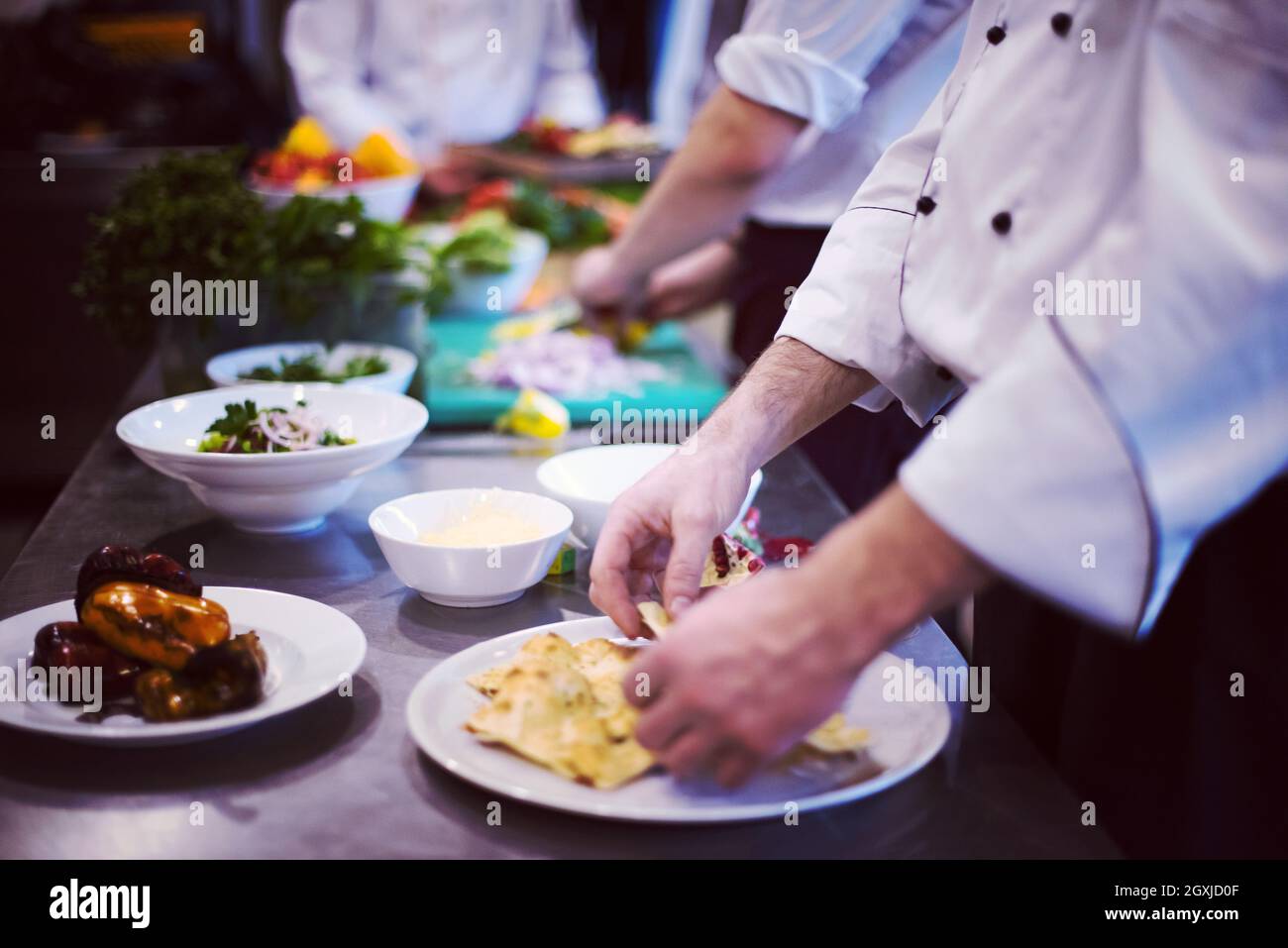 Professional team cooks and chefs preparing meal at busy hotel or ...