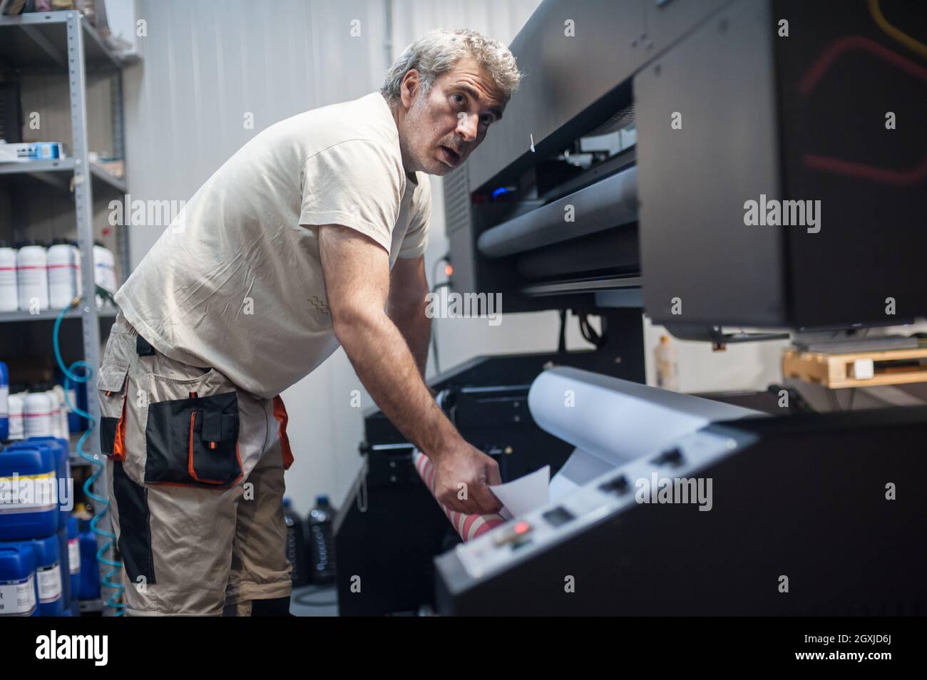Technician worker operator changes the paper roll on large premium ...