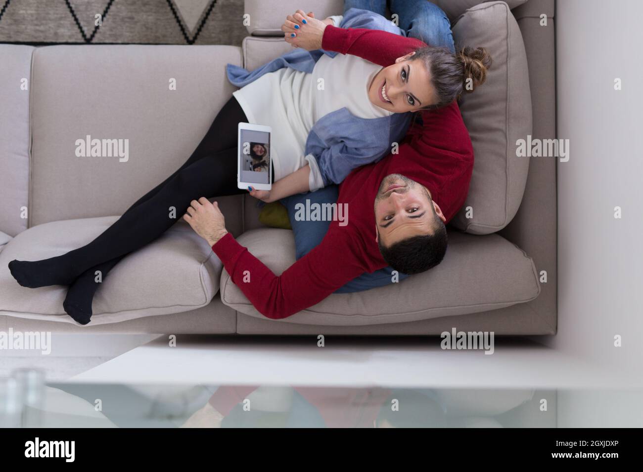 Young couple relaxing at home using tablet computers reading in the ...