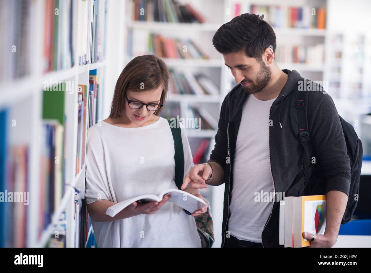 happy students couple in school library have discussion about book ...