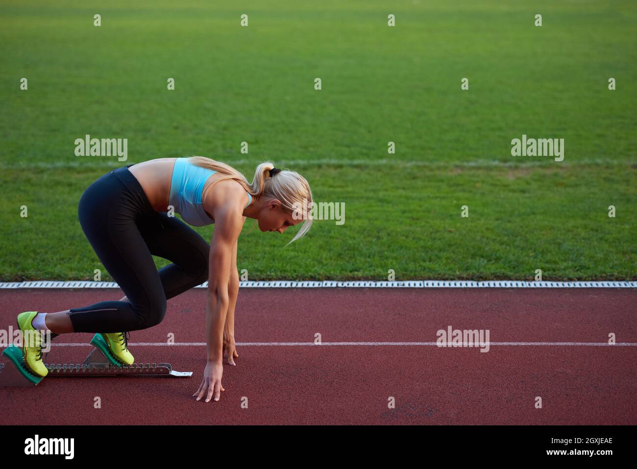 woman sprinter leaving starting blocks on the athletic track. Side view ...