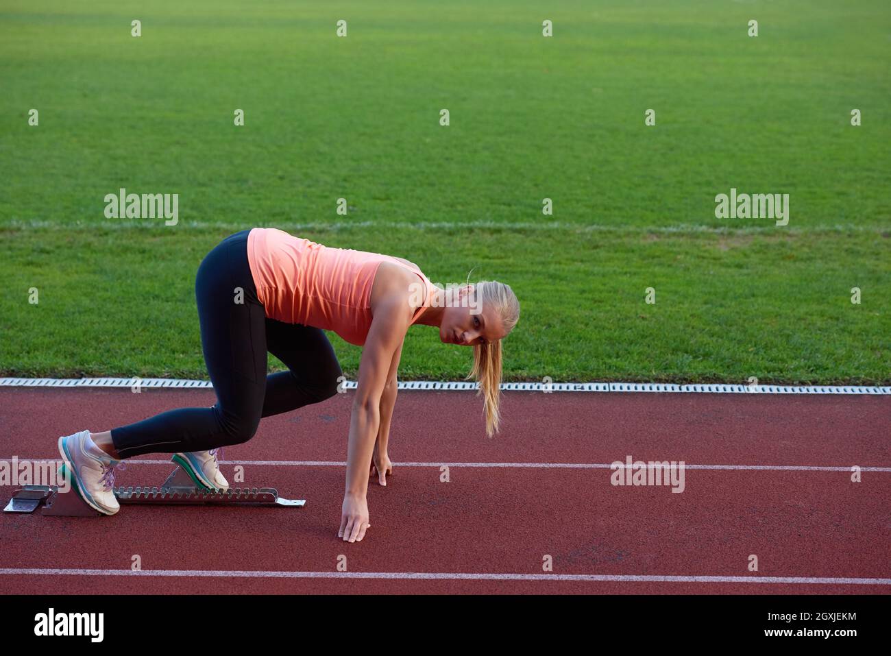 woman sprinter leaving starting blocks on the athletic track. Side view ...