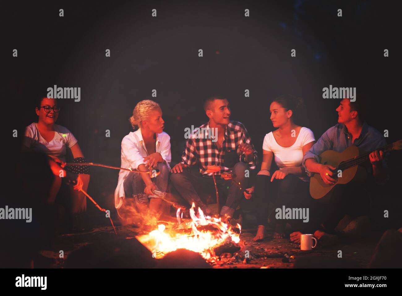 a group of happy young friends relaxing and enjoying summer evening ...