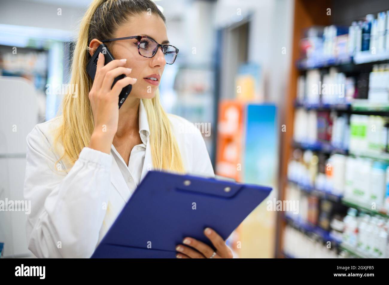 Female pharmacist talking on the phone with a customer in his store ...