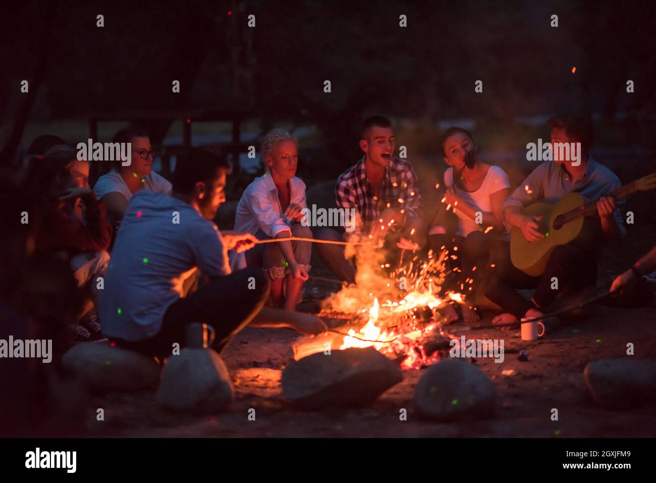 a group of happy young friends relaxing and enjoying summer evening ...