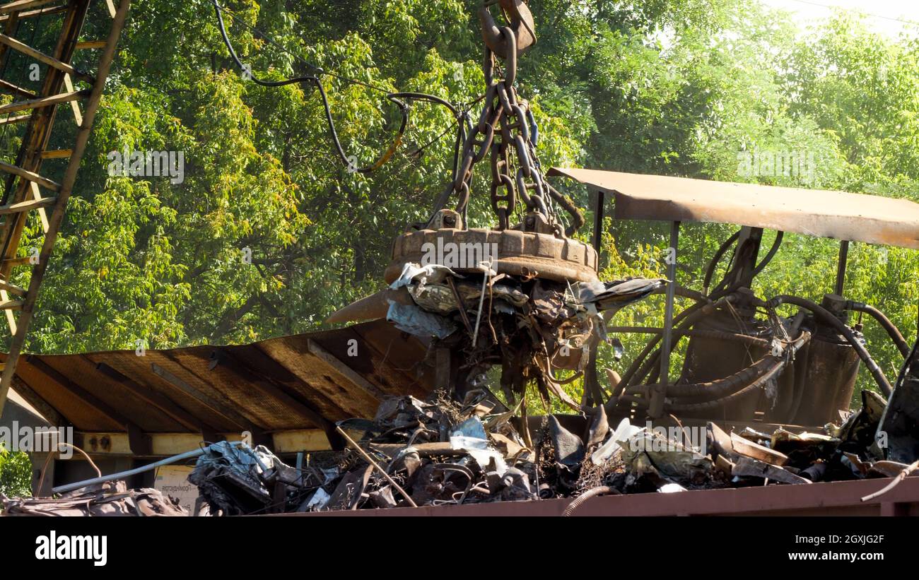 Electric magnet sorting metal waste from other rubbish on scrapyard ...