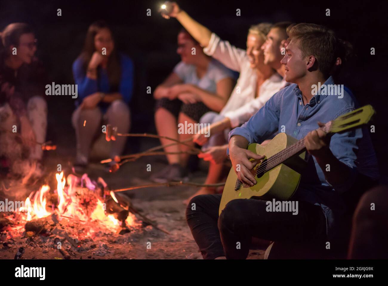 a group of happy young friends relaxing and enjoying summer evening ...