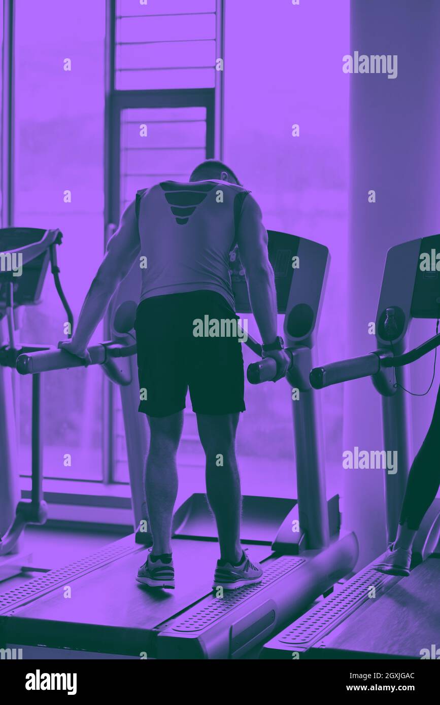 Handsome man running on the treadmill in modern gym duo tone Stock ...
