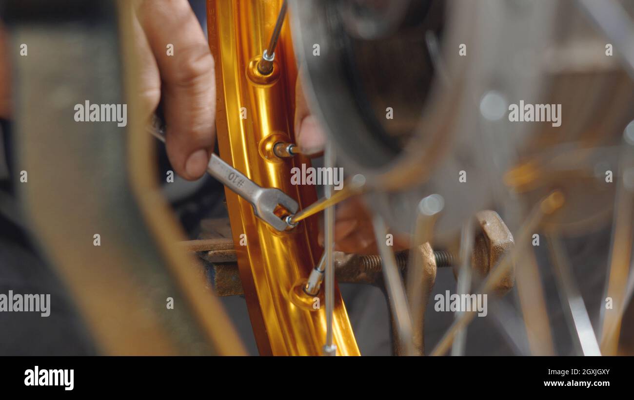 Technician man working motorcycle wheel has spokes weave up on mechanic ...