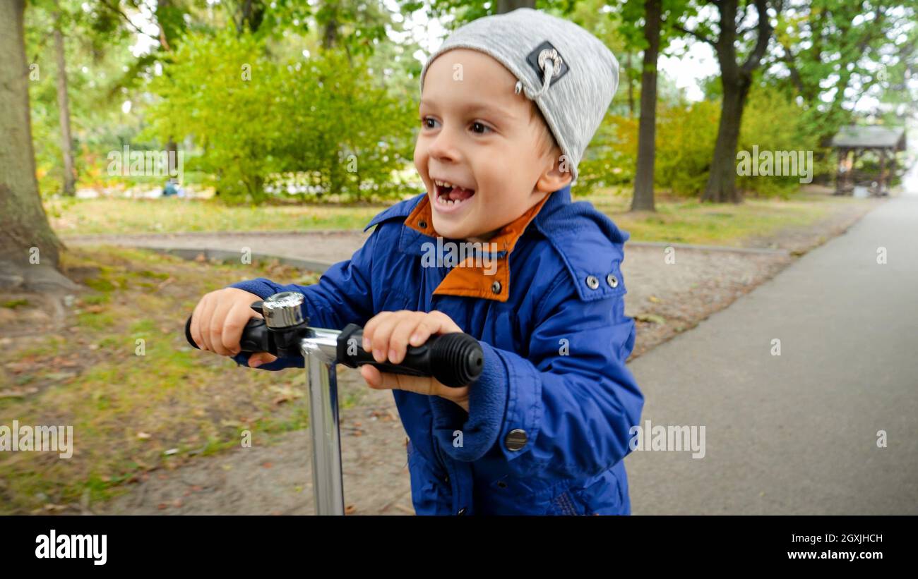 Portrait of laughing and smiling little boy holding steering handle on ...
