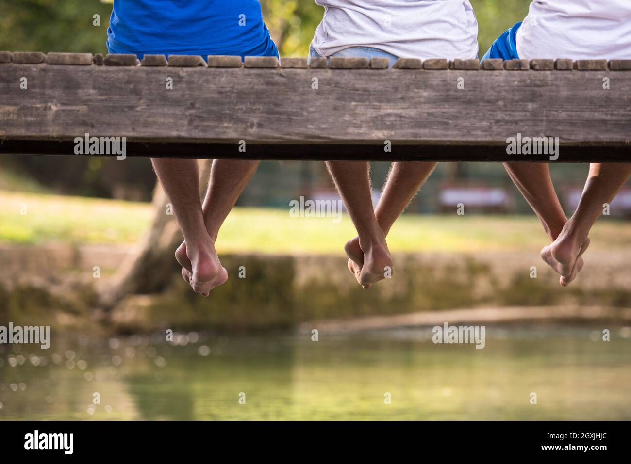 group of people sitting at wooden bridge over the river with a focus on ...