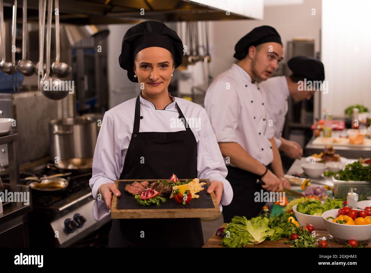 female Chef in hotel or restaurant kitchen holding grilled beef steak ...