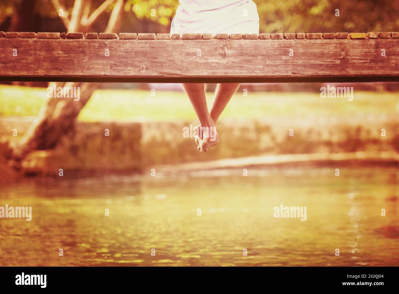 group of people sitting at wooden bridge over the river with a focus on ...