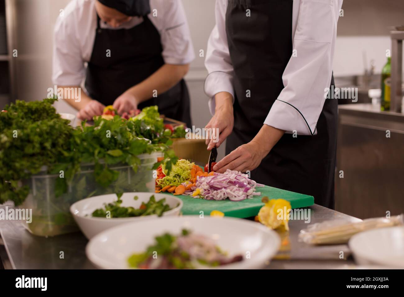Professional team cooks and chefs preparing meal at busy hotel or ...