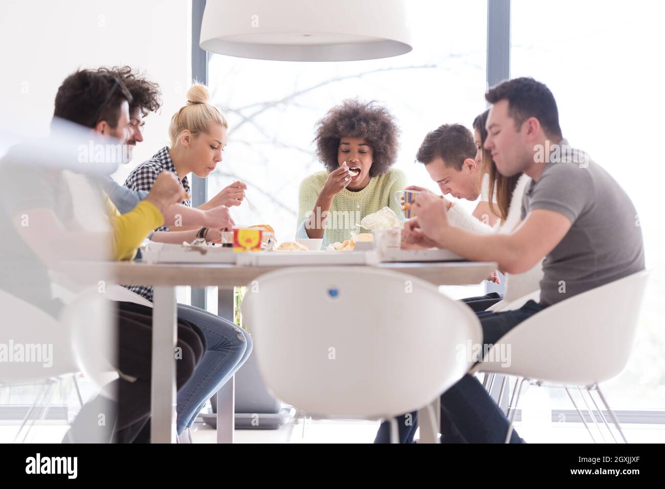 multiethnic group of happy friends spending time together with food and ...