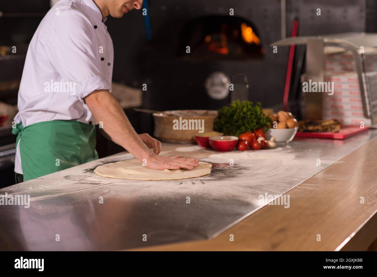 chef preparing dough for pizza rolling with hands on sprinkled with ...