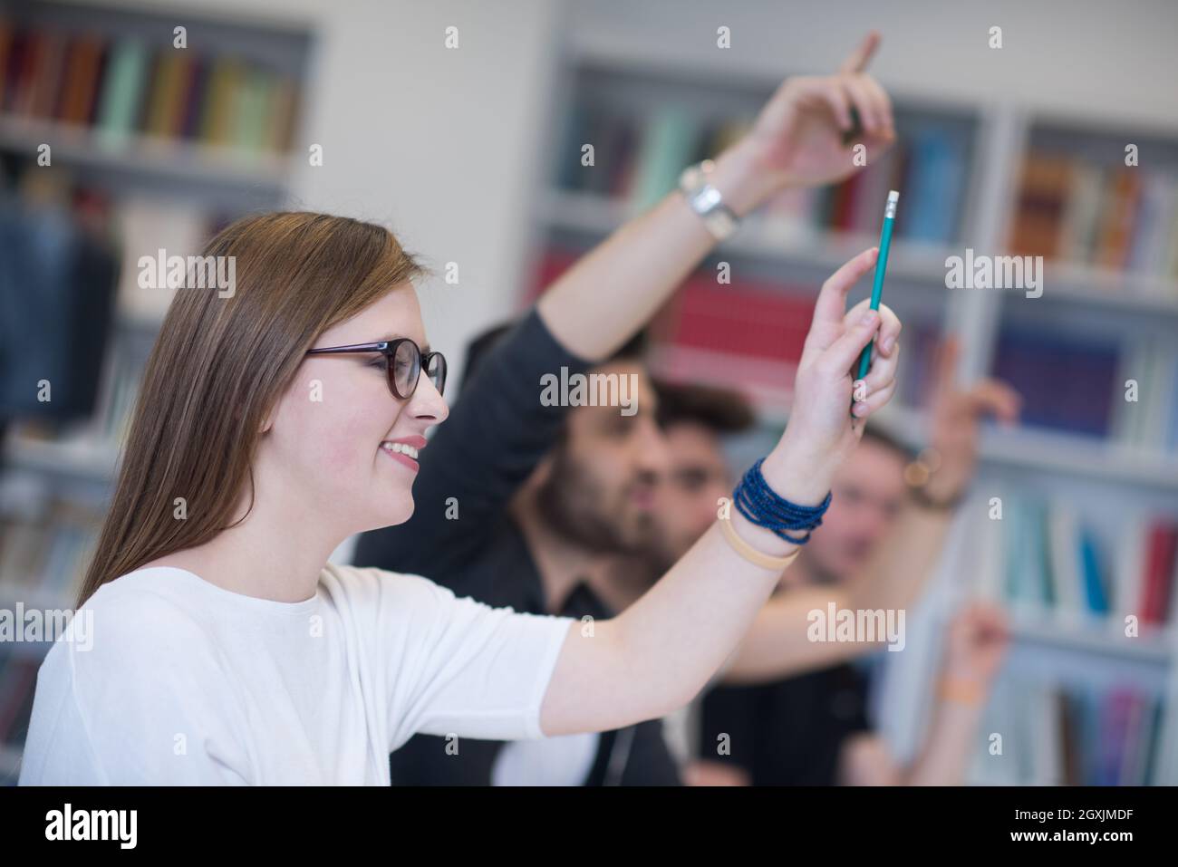 group of smart students raise hands up in school classroom on class ...