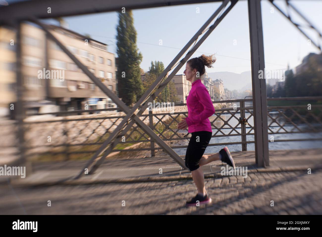 sporty woman running on sidewalk at early morning jogging with city ...
