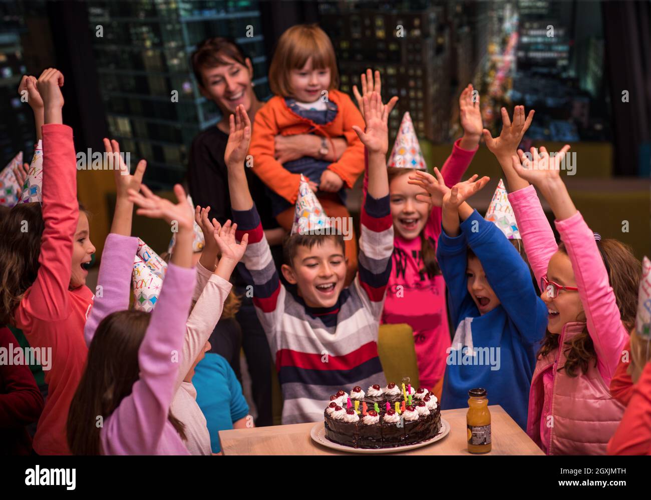young happy boy and group of his friends having birthday party with a ...