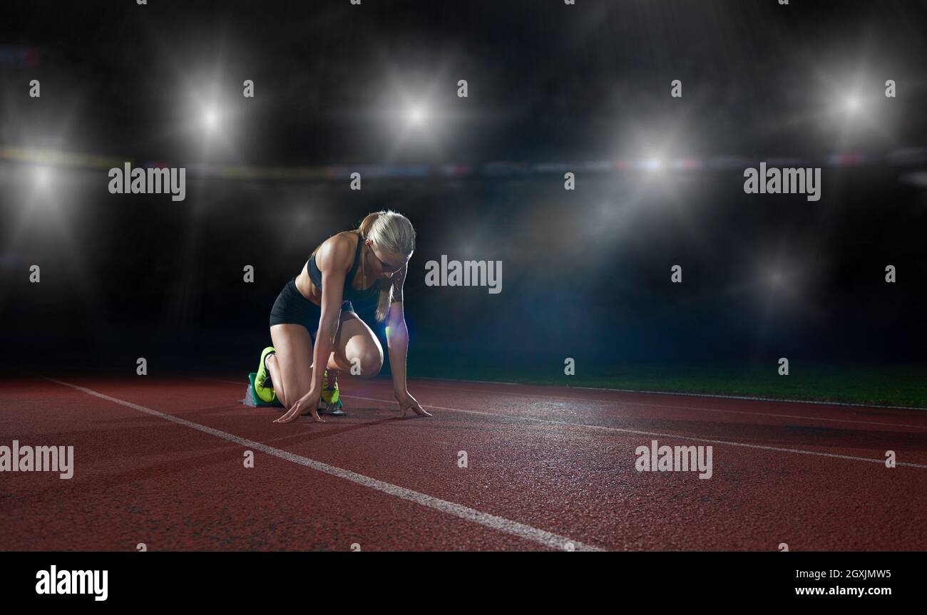 woman sprinter leaving starting blocks on the athletic track in front ...