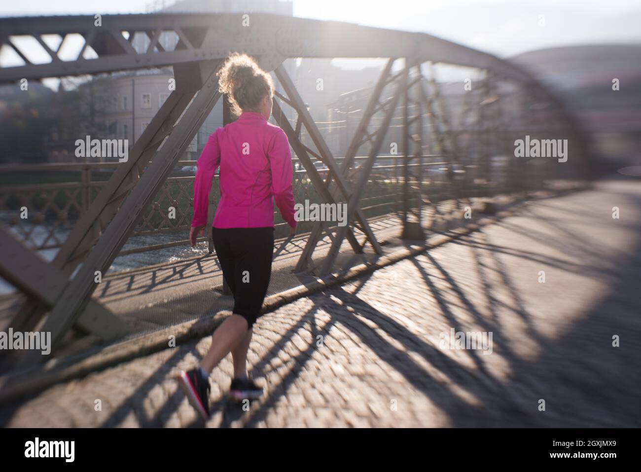 sporty woman running on sidewalk at early morning jogging with city ...