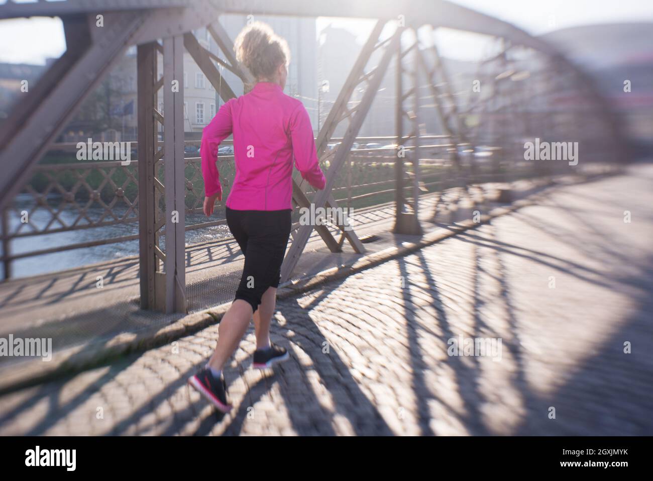 sporty woman running on sidewalk at early morning jogging with city ...
