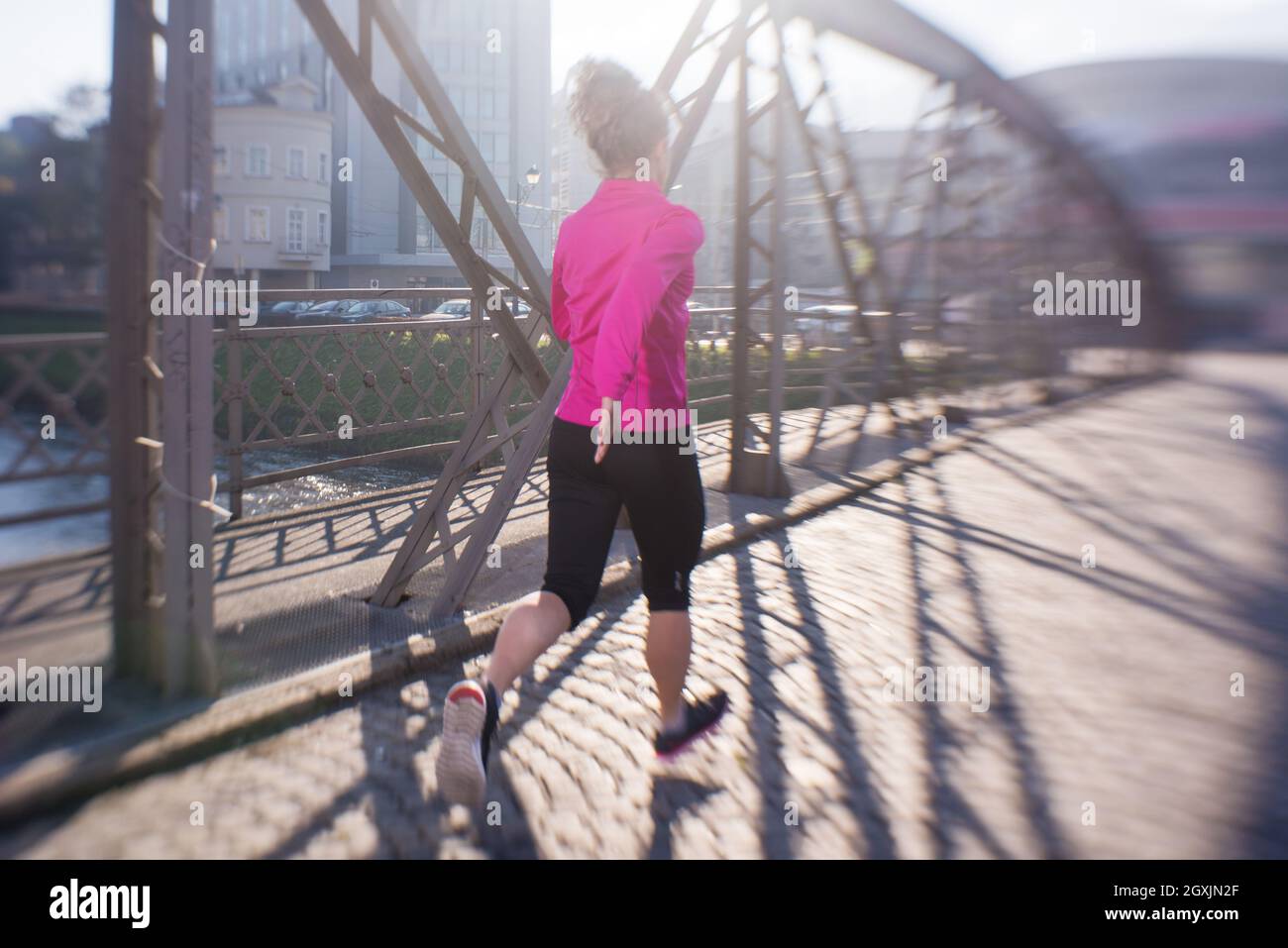 sporty woman running on sidewalk at early morning jogging with city ...