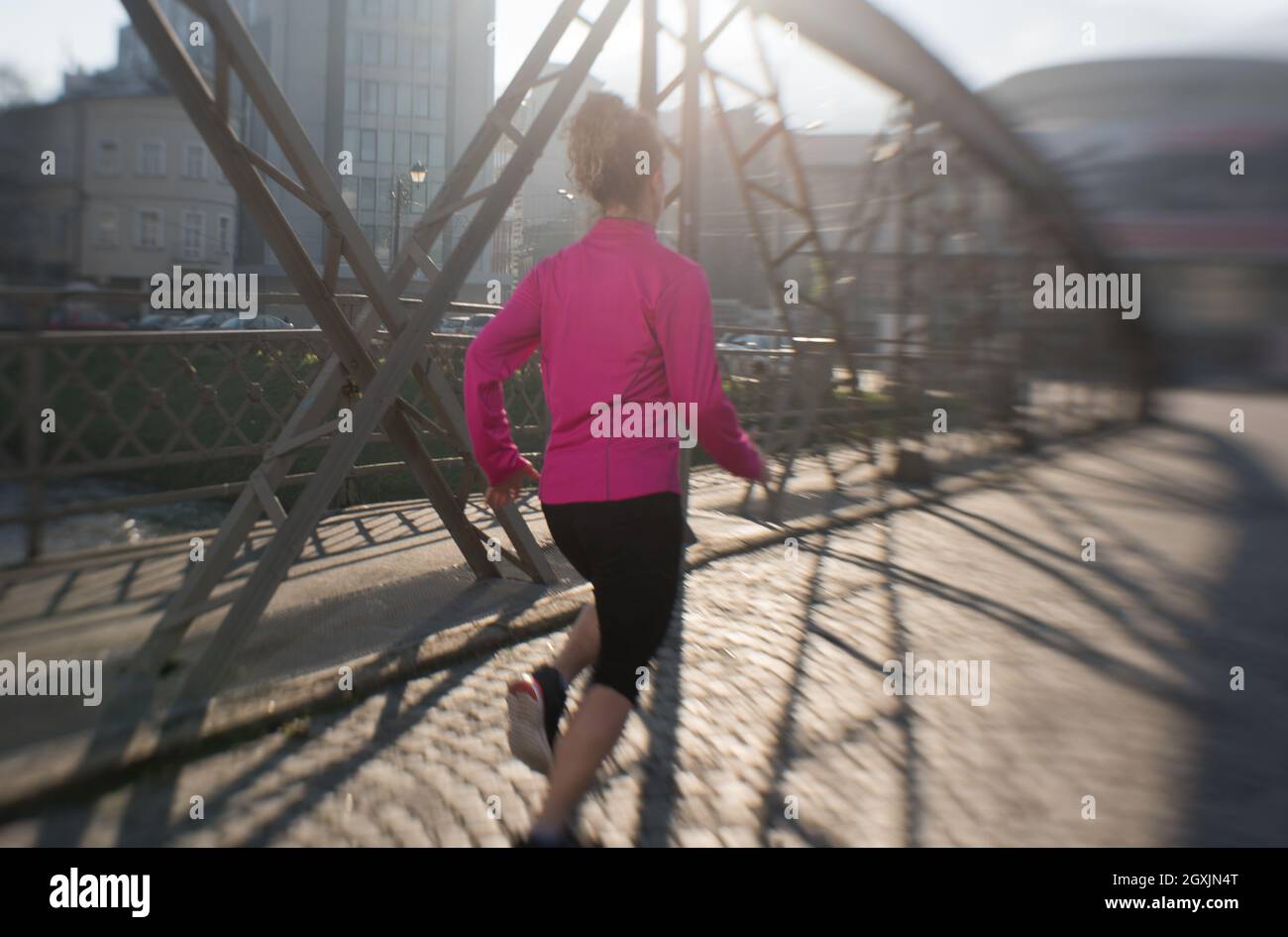 sporty woman running on sidewalk at early morning jogging with city ...