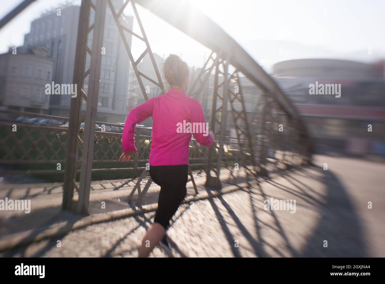 sporty woman running on sidewalk at early morning jogging with city ...