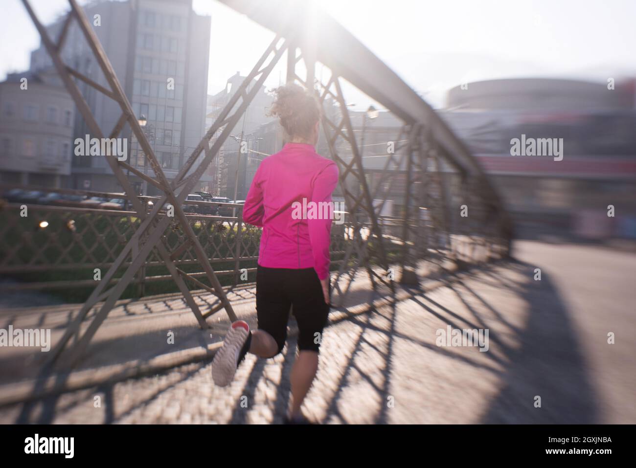 sporty woman running on sidewalk at early morning jogging with city ...