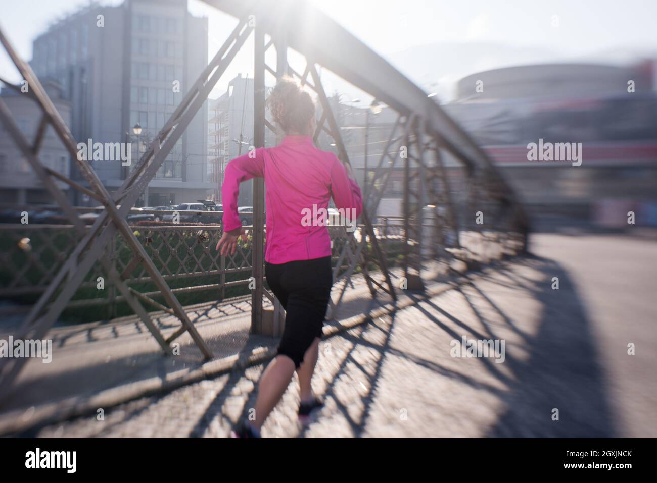 sporty woman running on sidewalk at early morning jogging with city ...