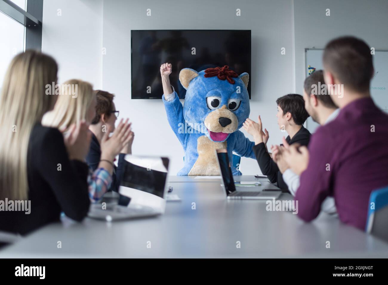 Boss dresed as teddy bear having fun with bussines people in modern ...