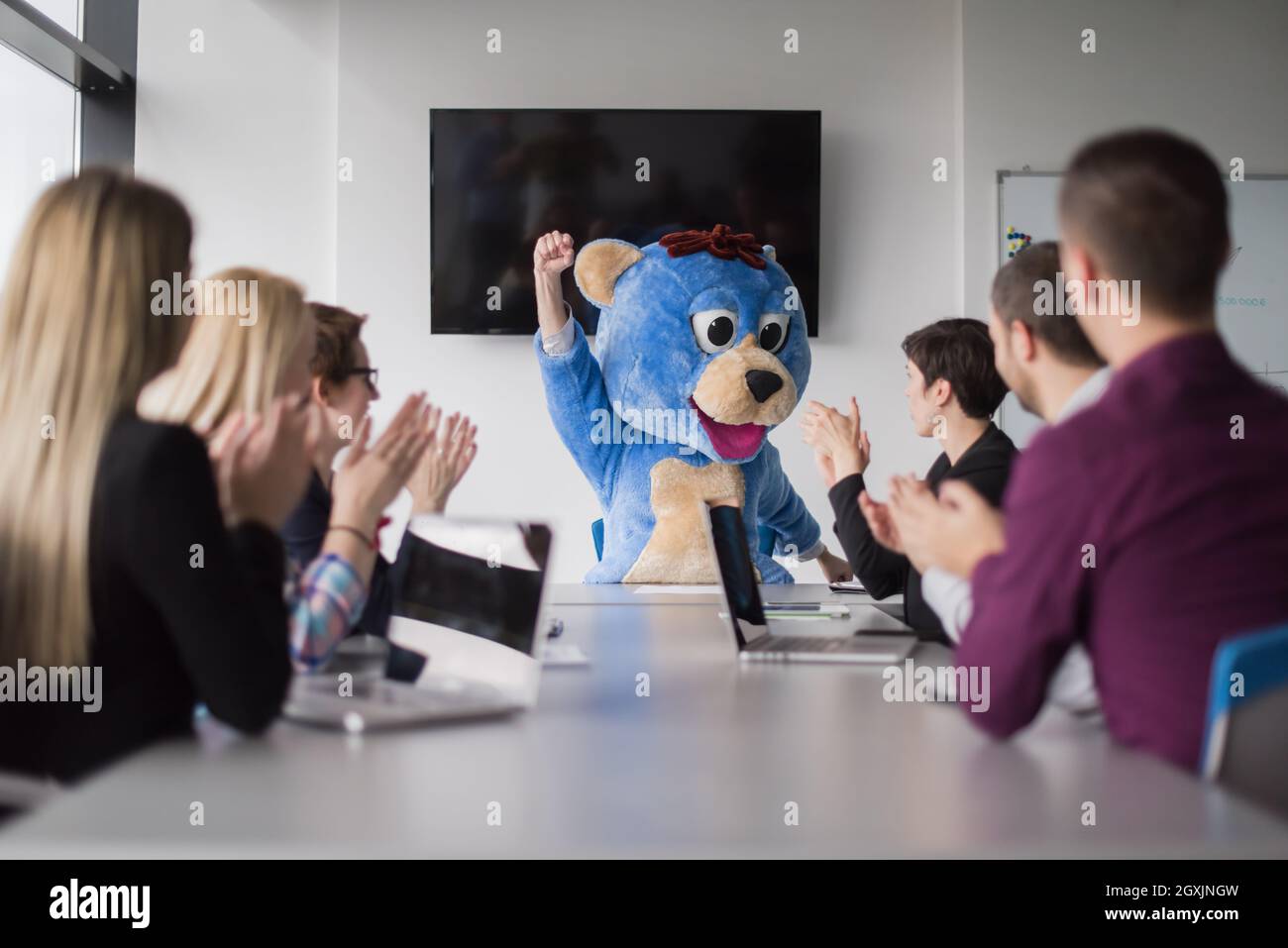 Boss dresed as teddy bear having fun with bussines people in modern ...