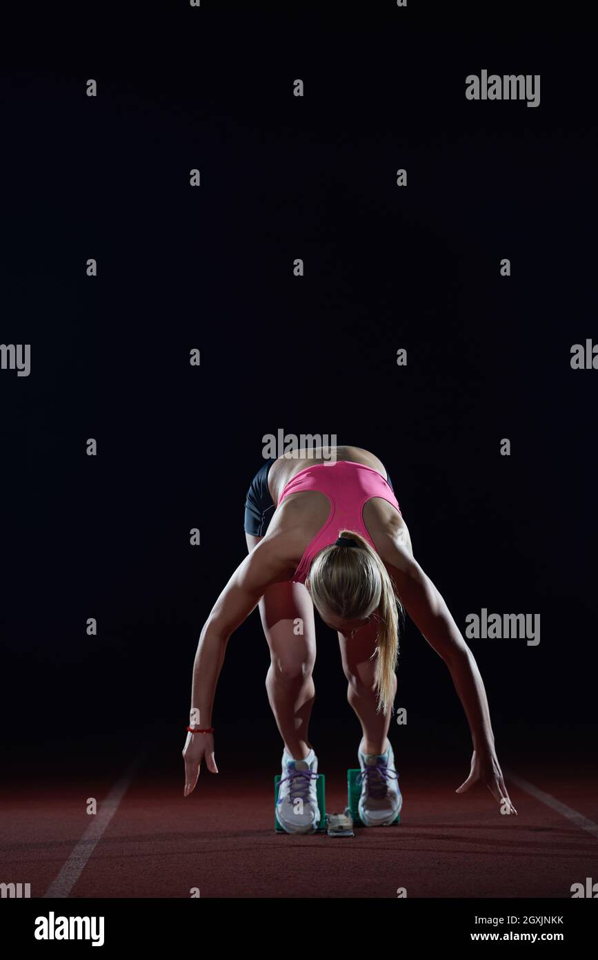 woman sprinter leaving starting blocks on the athletic track. Side view ...