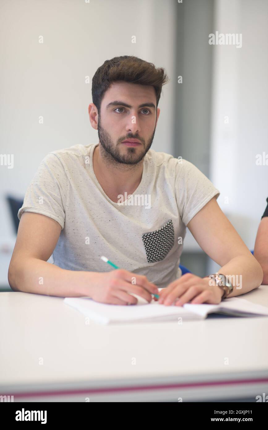 male student taking notes in classroom. business education concept ...