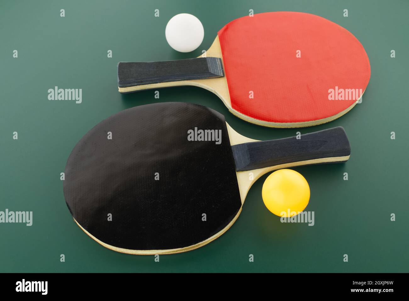 Red and black table tennis racks with a white and an yellow ping pong ...