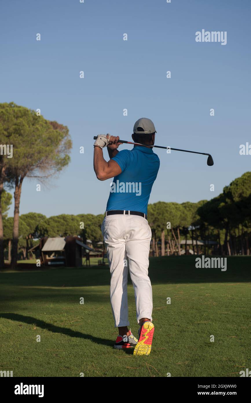 handsome sporty man, golf player hitting shot with club on course at ...