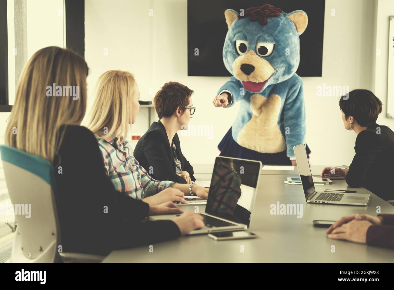 Boss dresed as teddy bear having fun with bussines people in modern ...