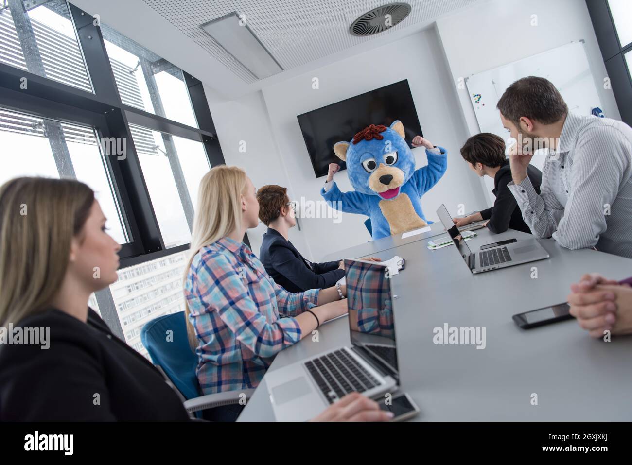 Boss dresed as teddy bear having fun with bussines people in modern ...